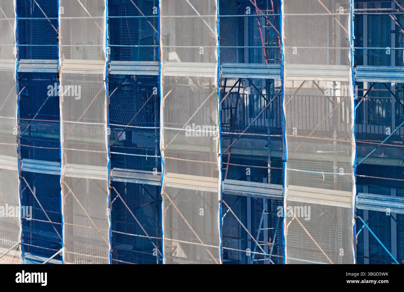 scaffolding against residential building covered with blue and white ...