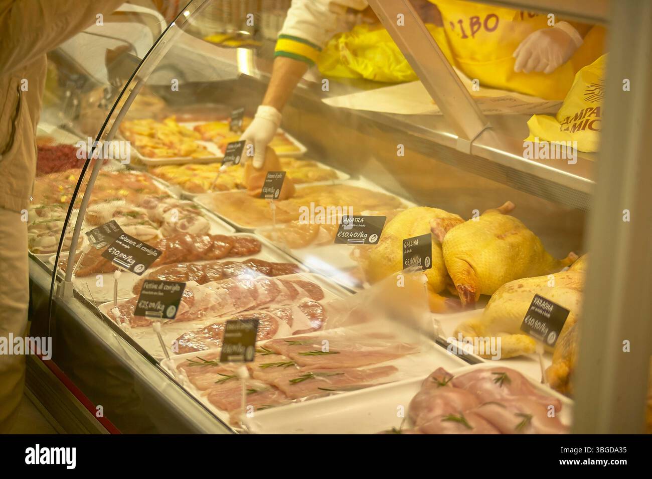 Milan, Italy 1 January 2025: Butcher wearing gloves arranging fresh ...