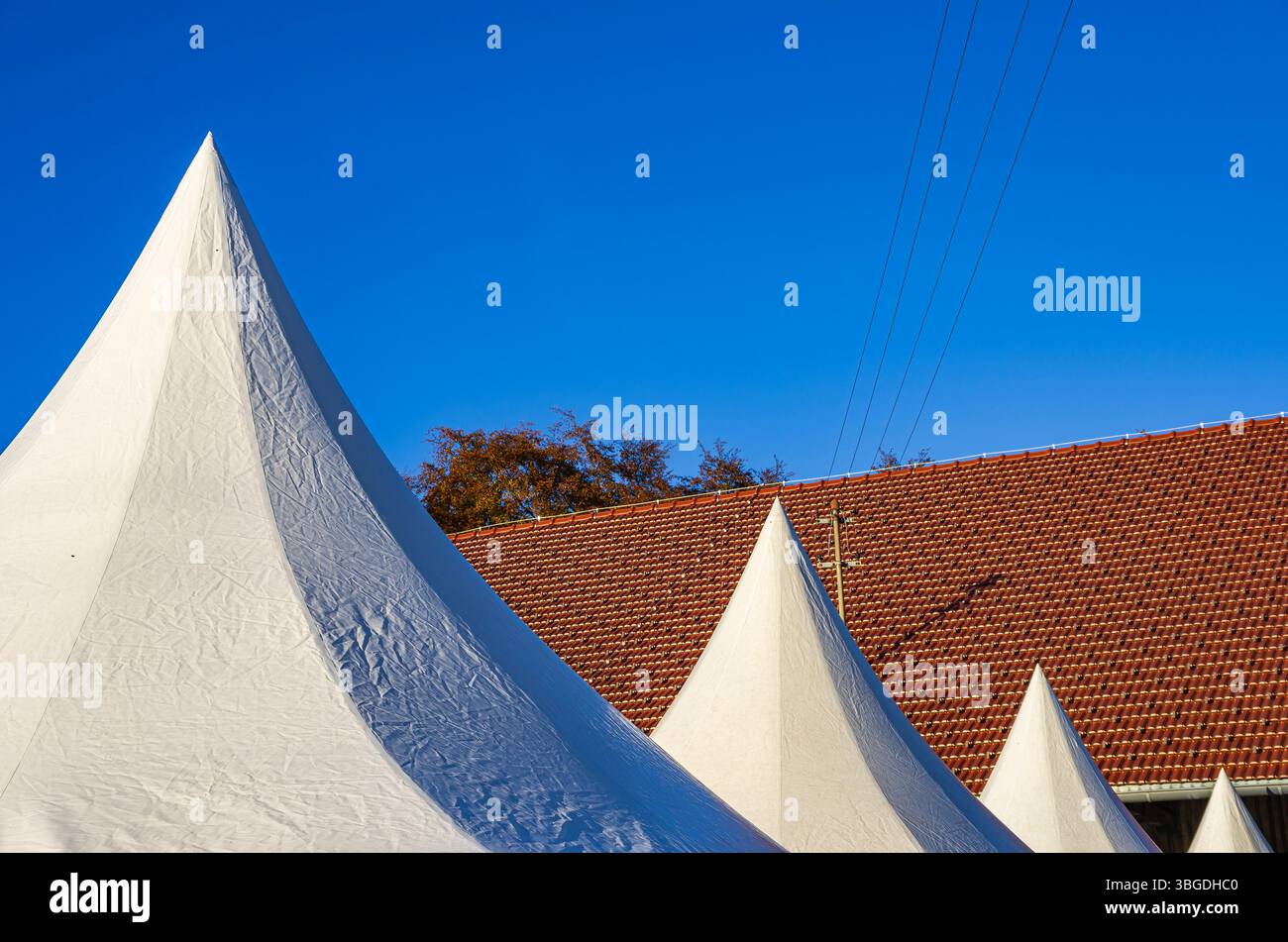 A row of pointed tents in front of a roof structure Stock Photo - Alamy