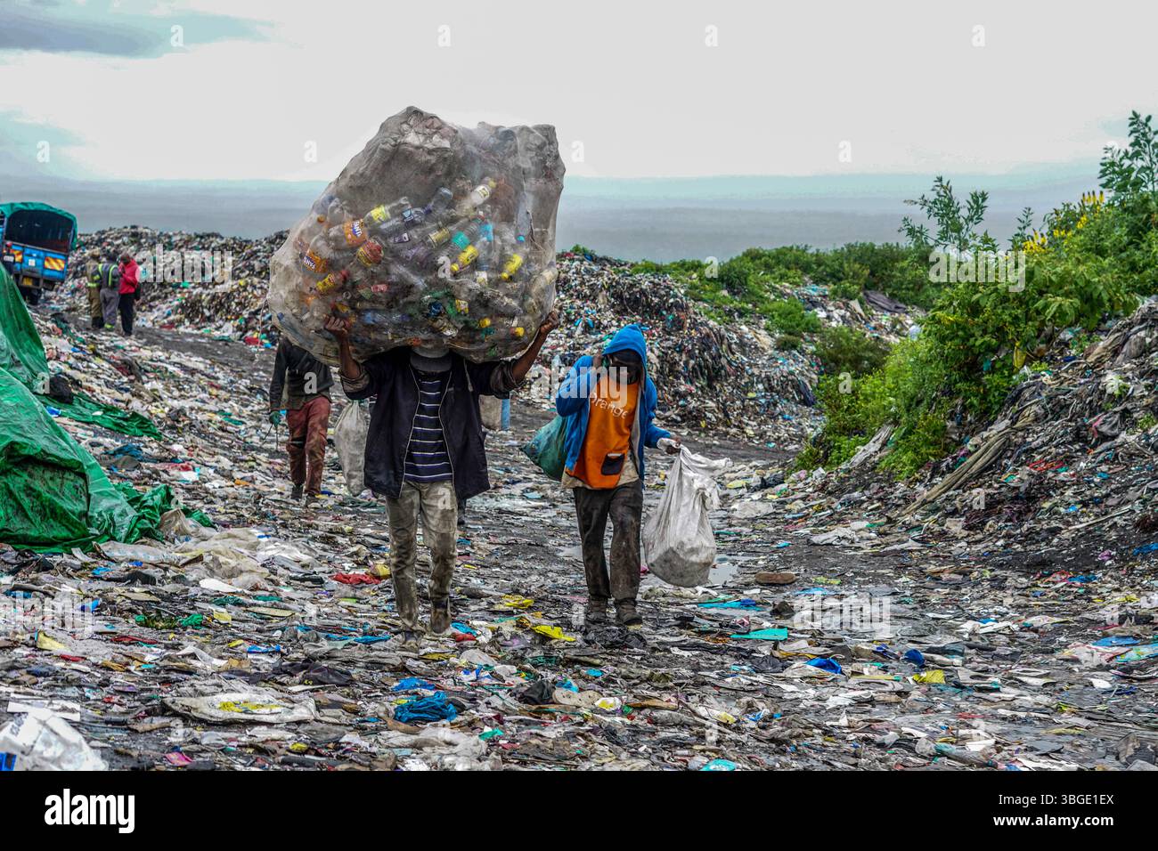 Informal waste workers carry materials to recycle at Gioto dumpsite ...