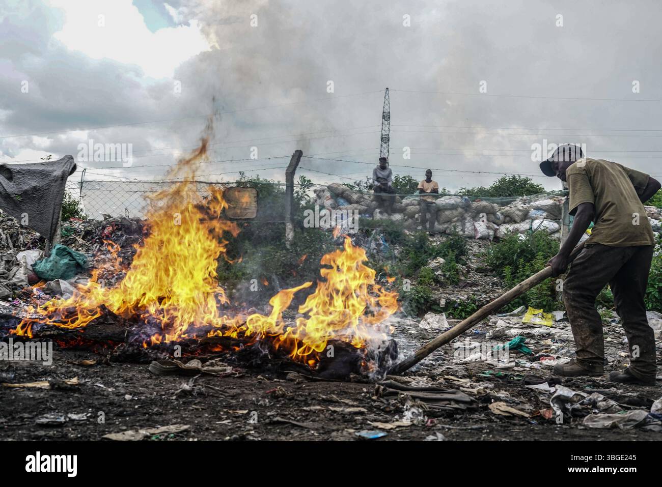 An informal waste worker burns a mattress to retrieve metal wires at ...