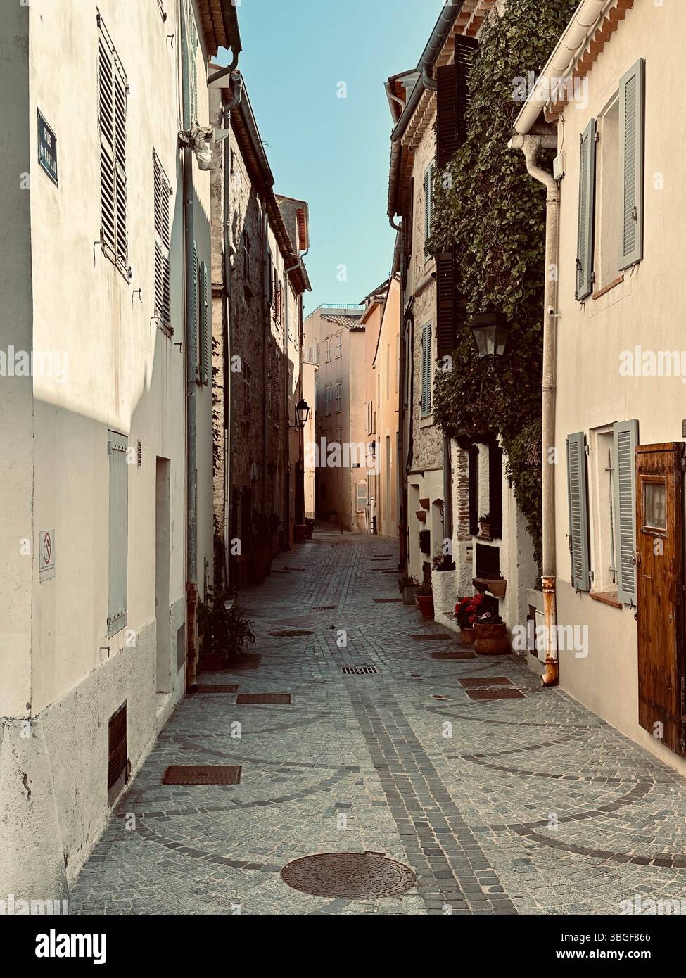 Quiet pedestrian street in a historic European town, with sunlit walls ...