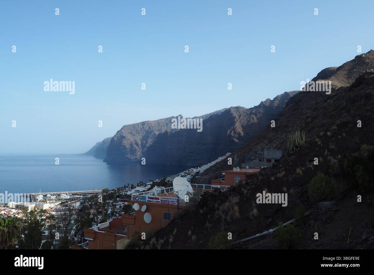Hillside Coastal Town with Ocean View and Cliffs under Clear Blue Sky ...