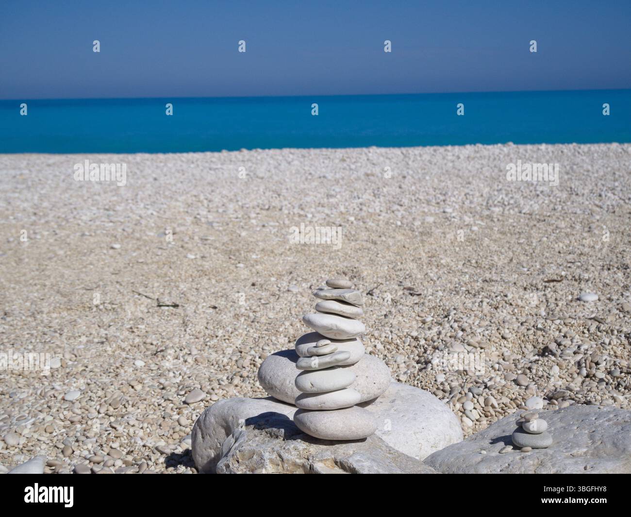 Coastal scene with white stone towers, calm sea, and beach Stock Photo ...