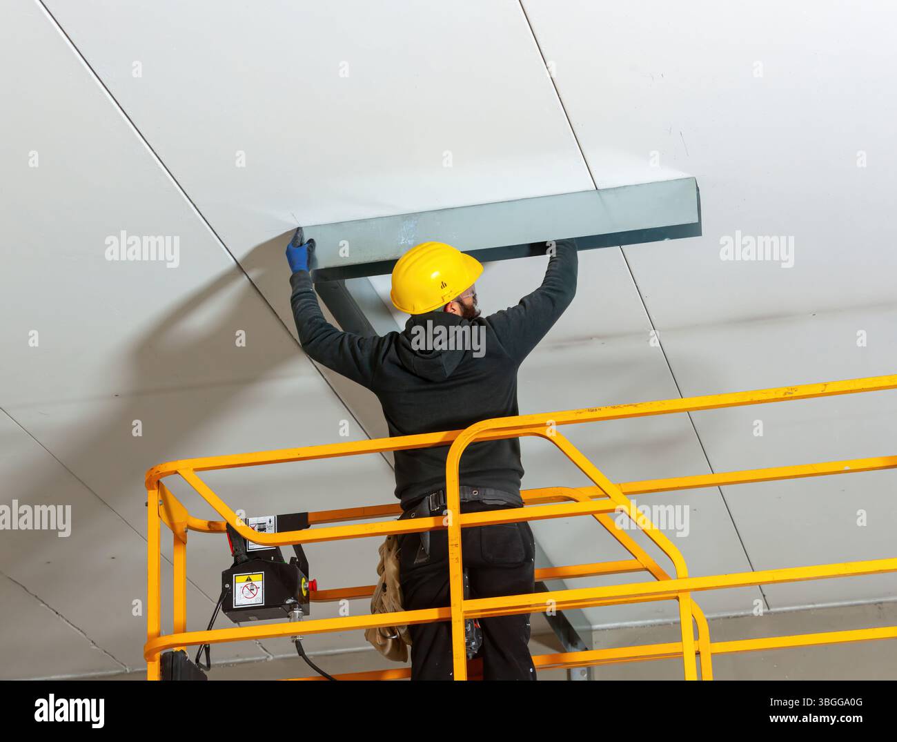 Construction worker on aerial work platform installing metal profile ...