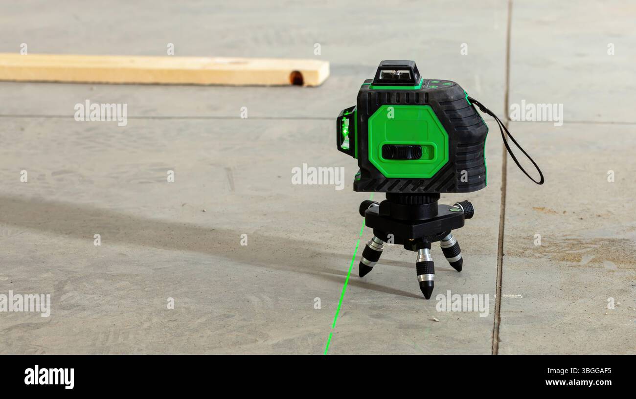 Green laser level tool projecting a bright line on a concrete floor ...