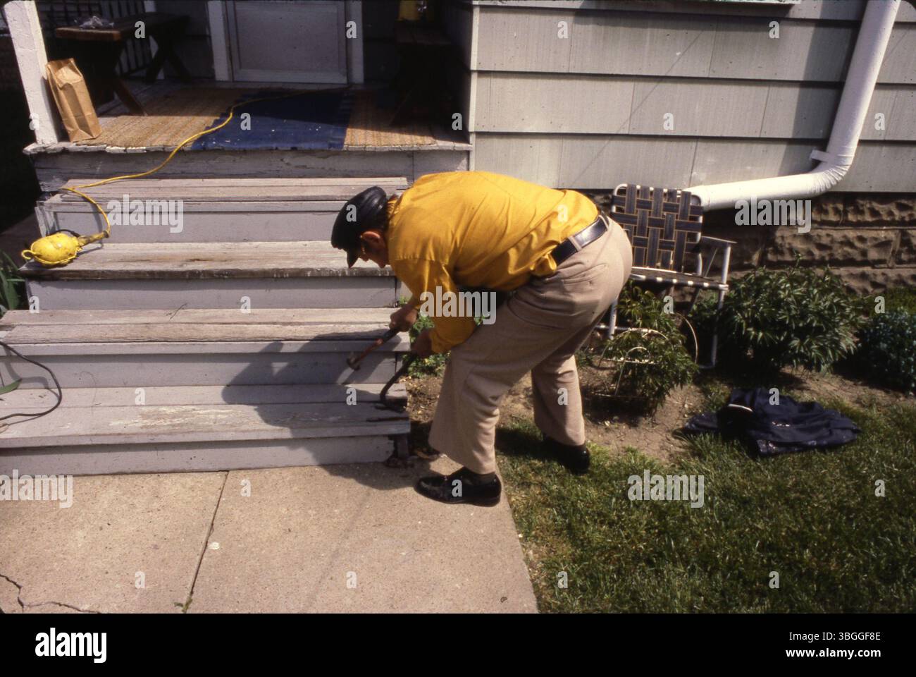 A worker provides maintenance to exterior wooden steps, performing ...