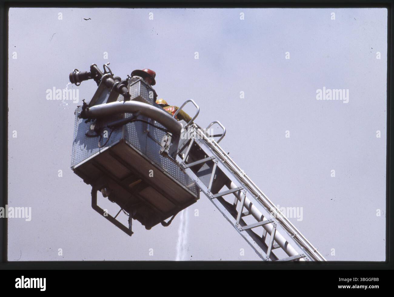 A firefighter stands in the bucket of a ladder truck circa 1981. The ...