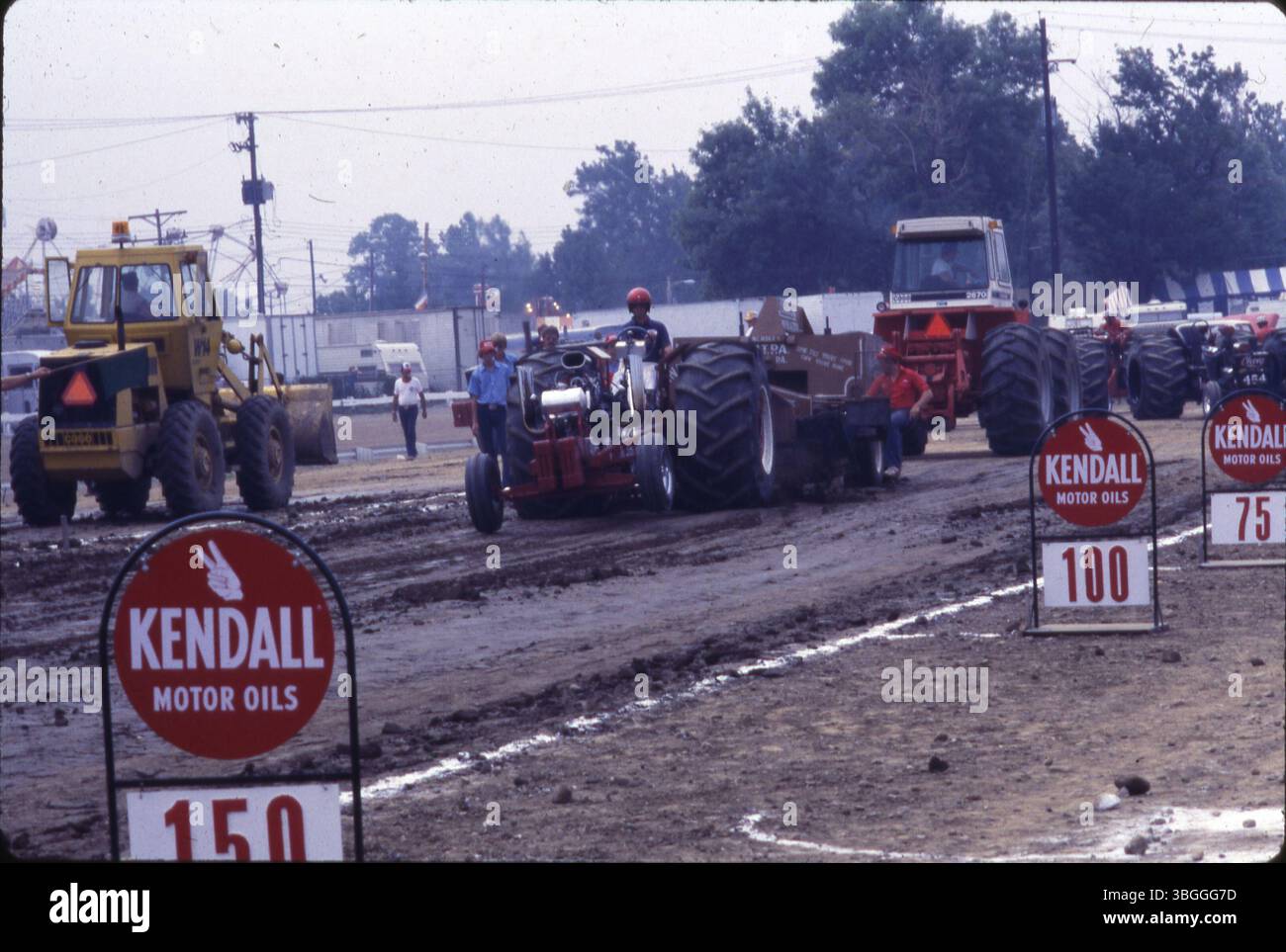 A driver wearing a blue shirt and red helmet competes in the tractor ...