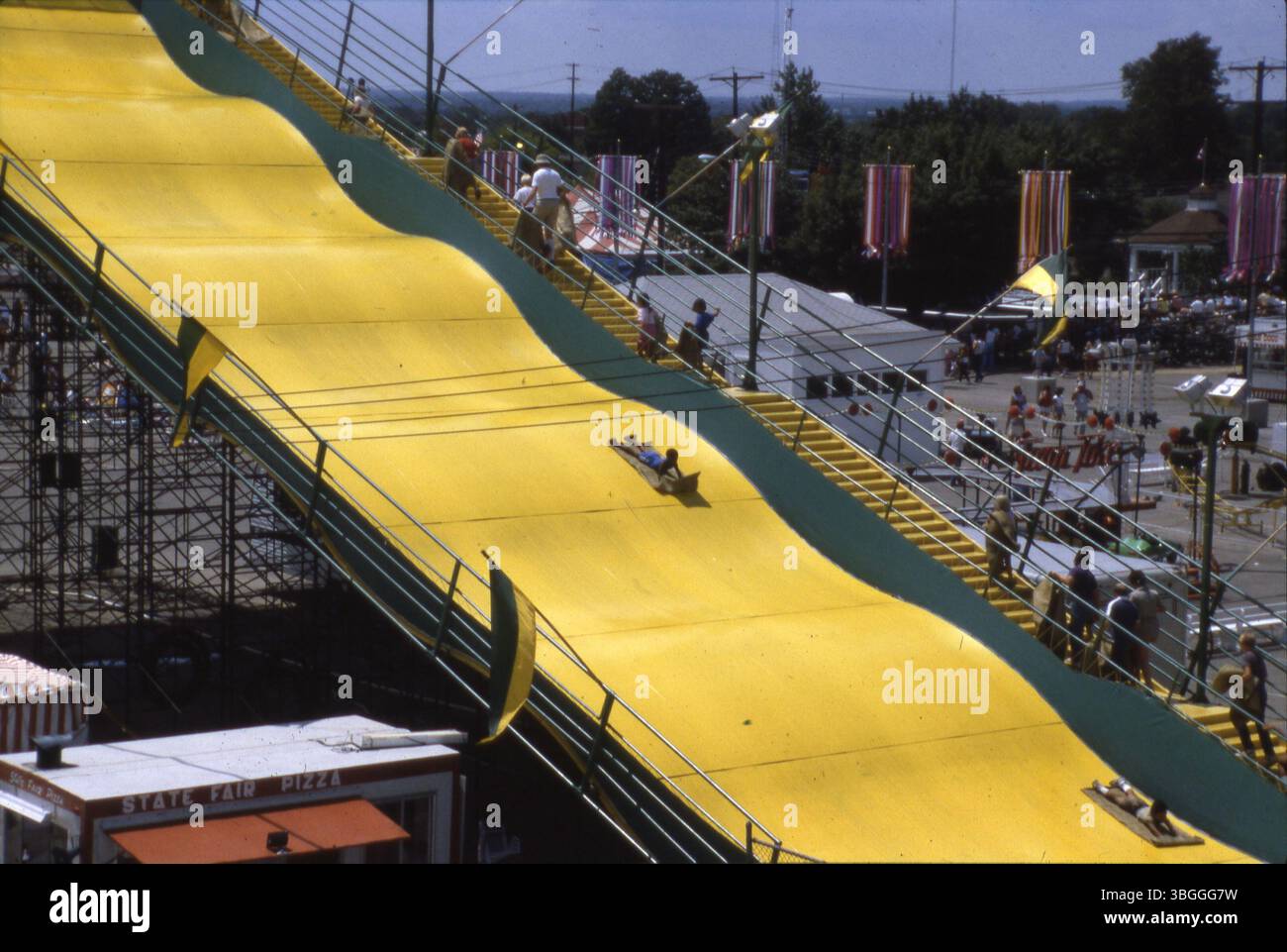 Two children ride down the yellow Giant Slide on their stomachs at the ...