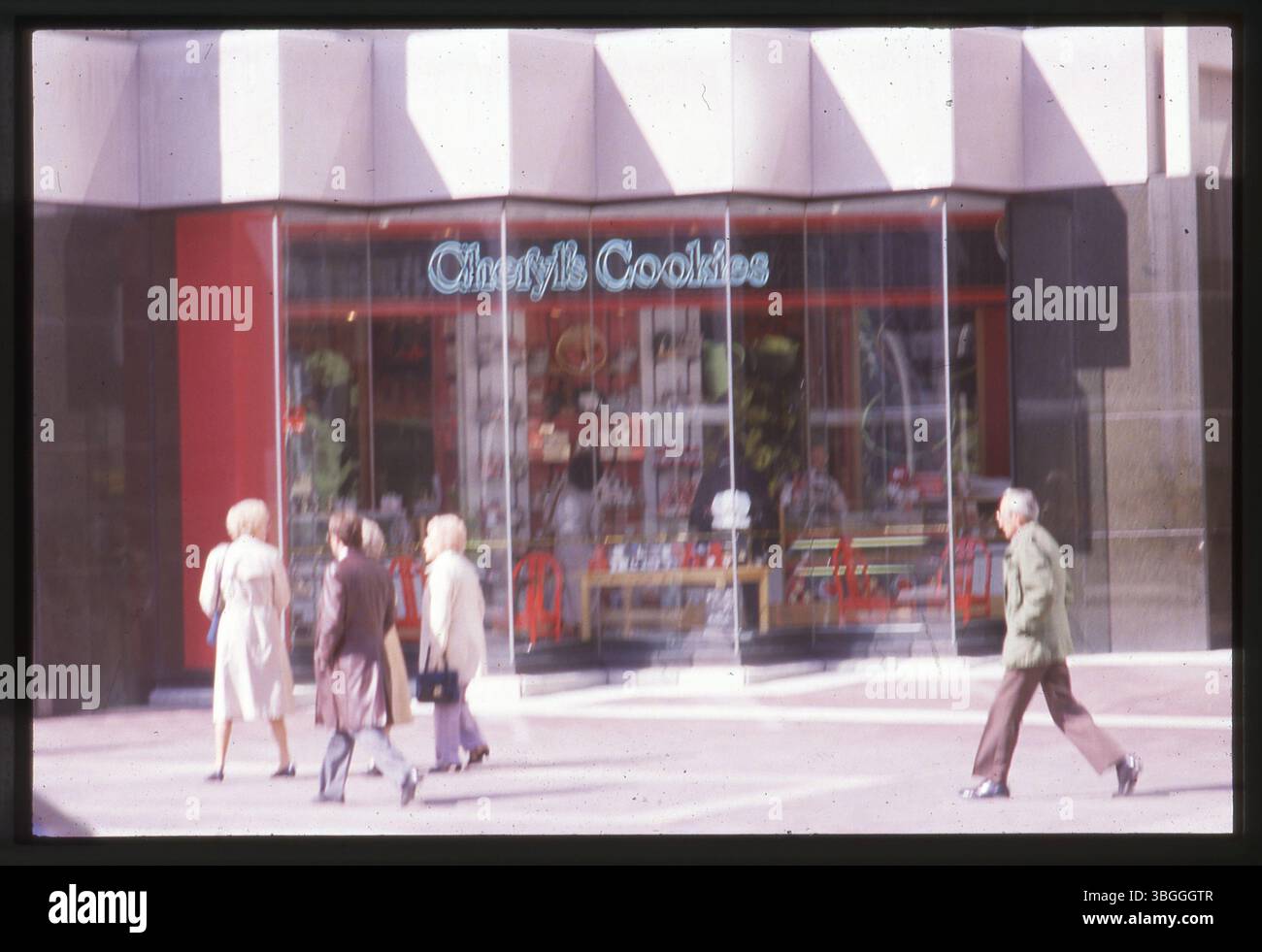 A view of pedestrians walking past the glass storefront of Cheryl's ...