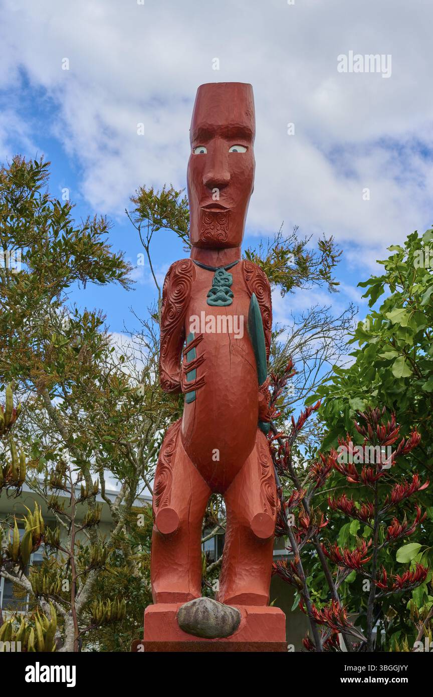 Red MAori wooden statue with detailed carvings and a distinctive face ...