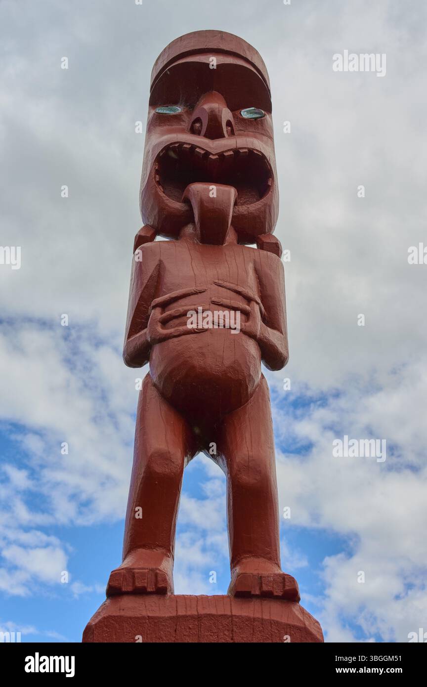Red wooden figure of mAori art with expressive face and hands on ...