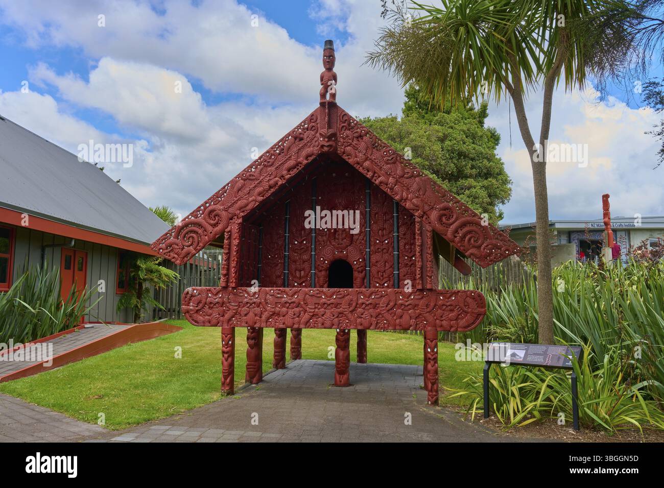 Small Maori building with red carvings surrounded by palm trees, New ...