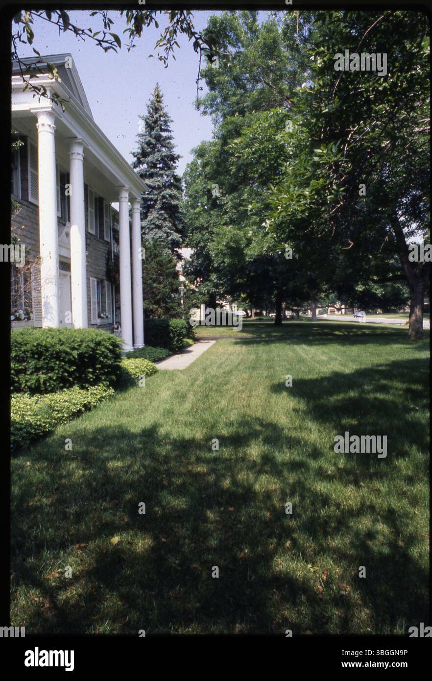 An unidentified street scene features a two-story house with four tall ...