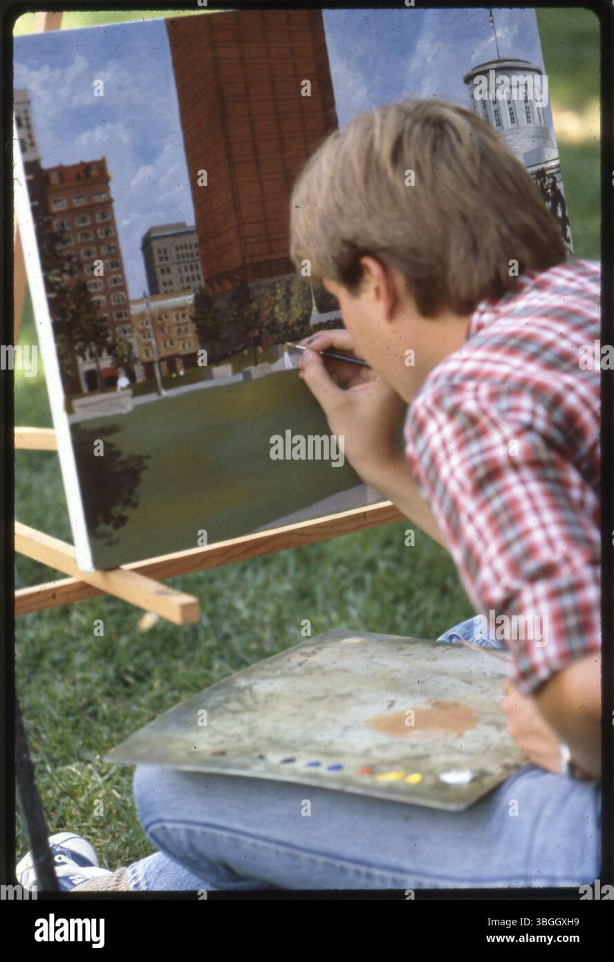 An artist works on a painting of the Ohio Statehouse while seated on ...