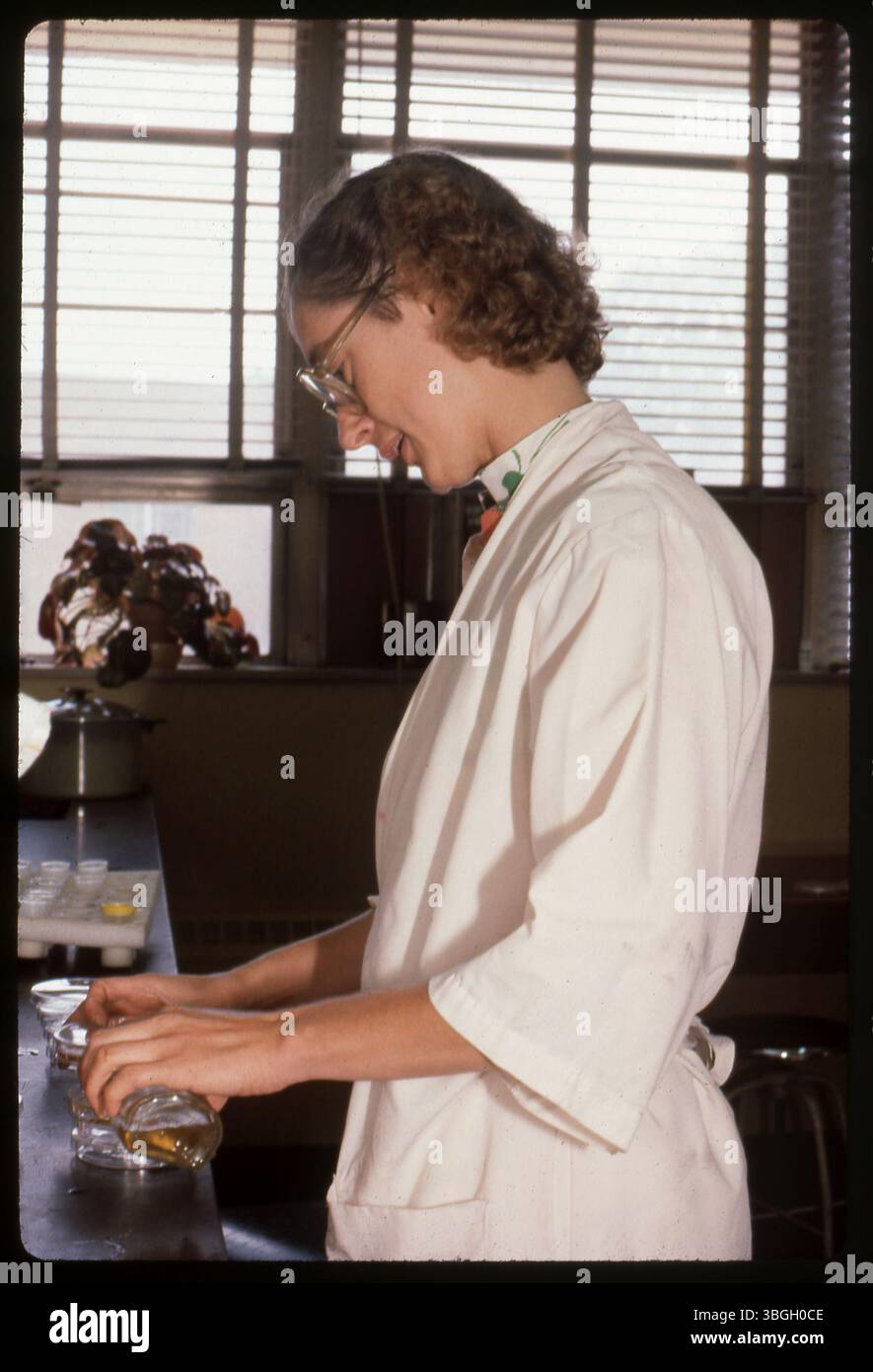 A female scientist wearing glasses and a white lab coat works at a ...