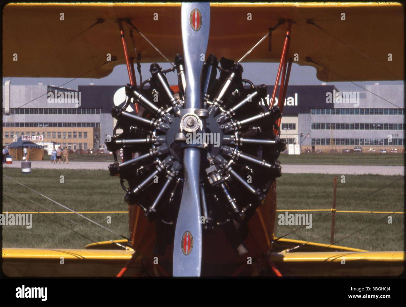 An orange biplane with yellow wings and a close view of the propellers ...