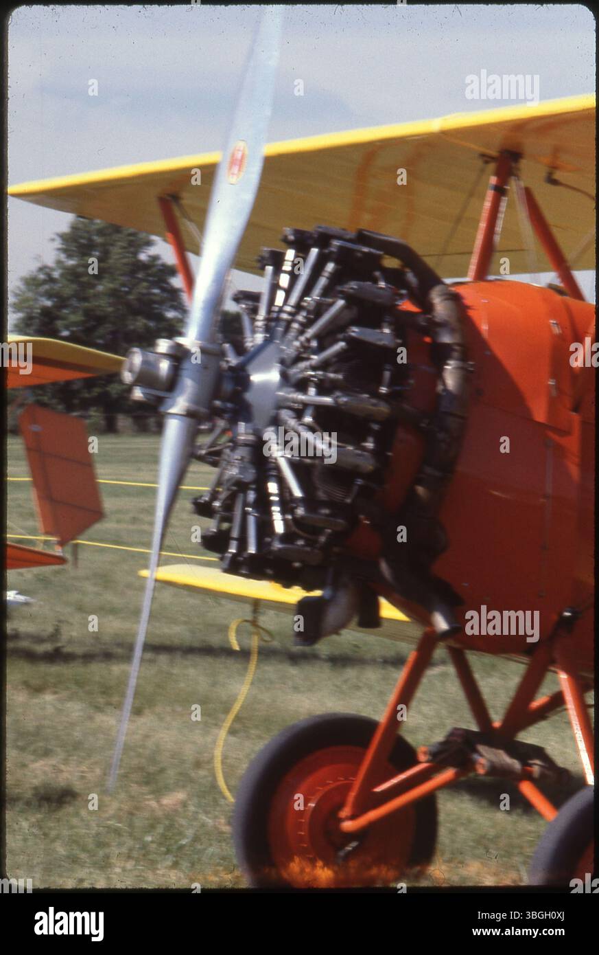 An orange biplane with yellow wings and a prominent propeller is ...