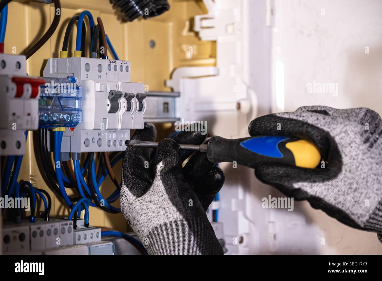 Detailed view of gloved hands adjusting a circuit breaker with a ...