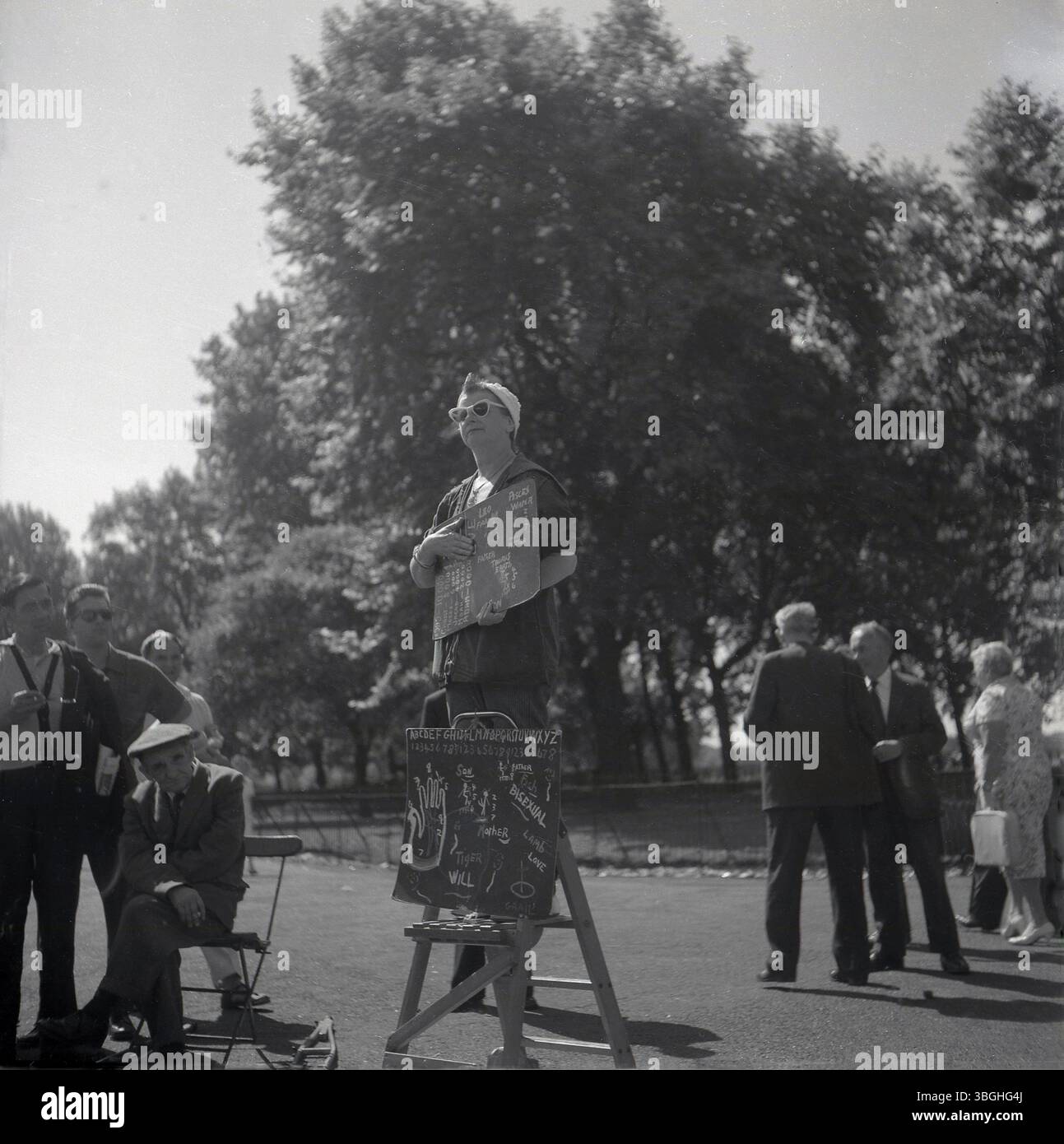 1950s, historical, leader on a small step- ladder, holding board ...
