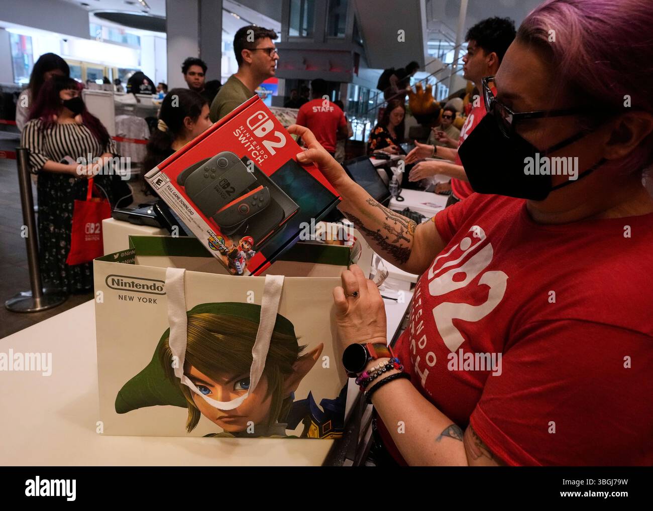 A Nintendo store cashier places a Switch 2 in a bag for a customer at ...