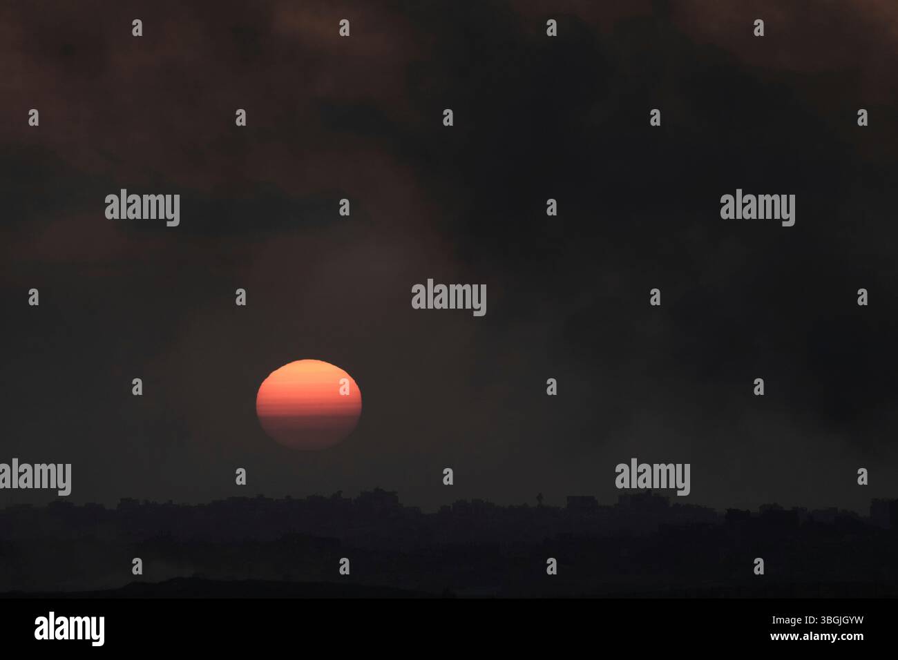 The sun sets as smoke from Israeli bombardment billows over buildings ...