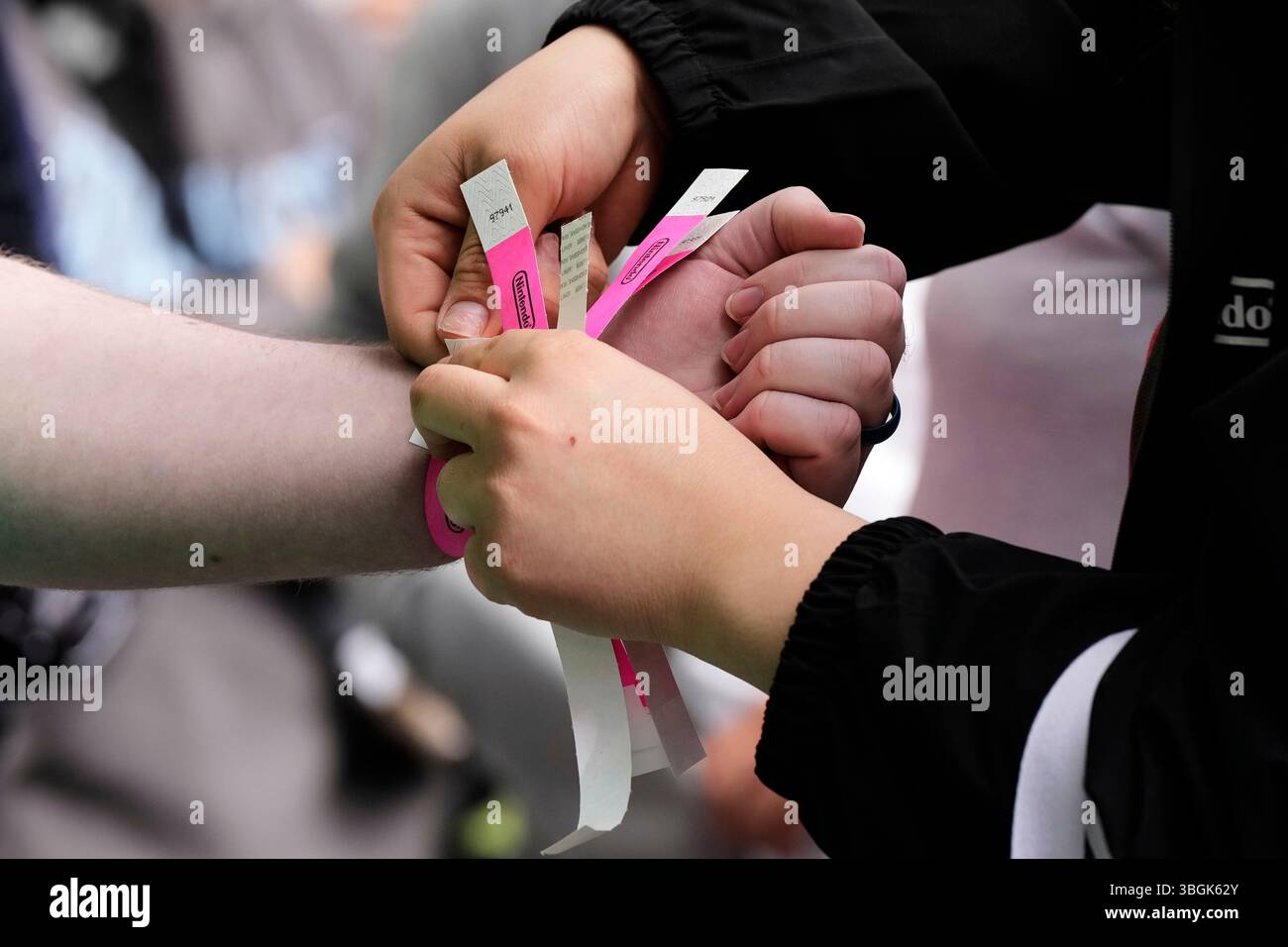 A Nintendo store employee attaches a wristband for a person waiting in ...