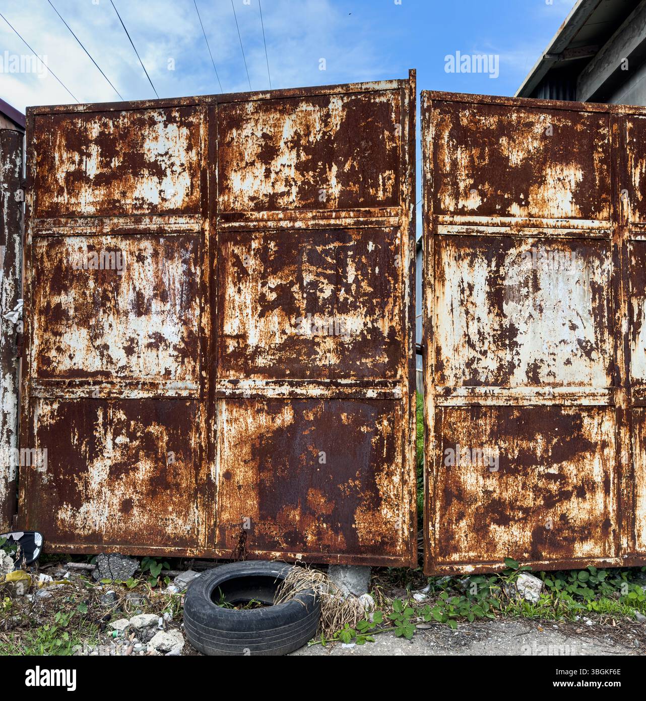 Old rusty metal gates with corrosion, peeling paint and urban debris on ...