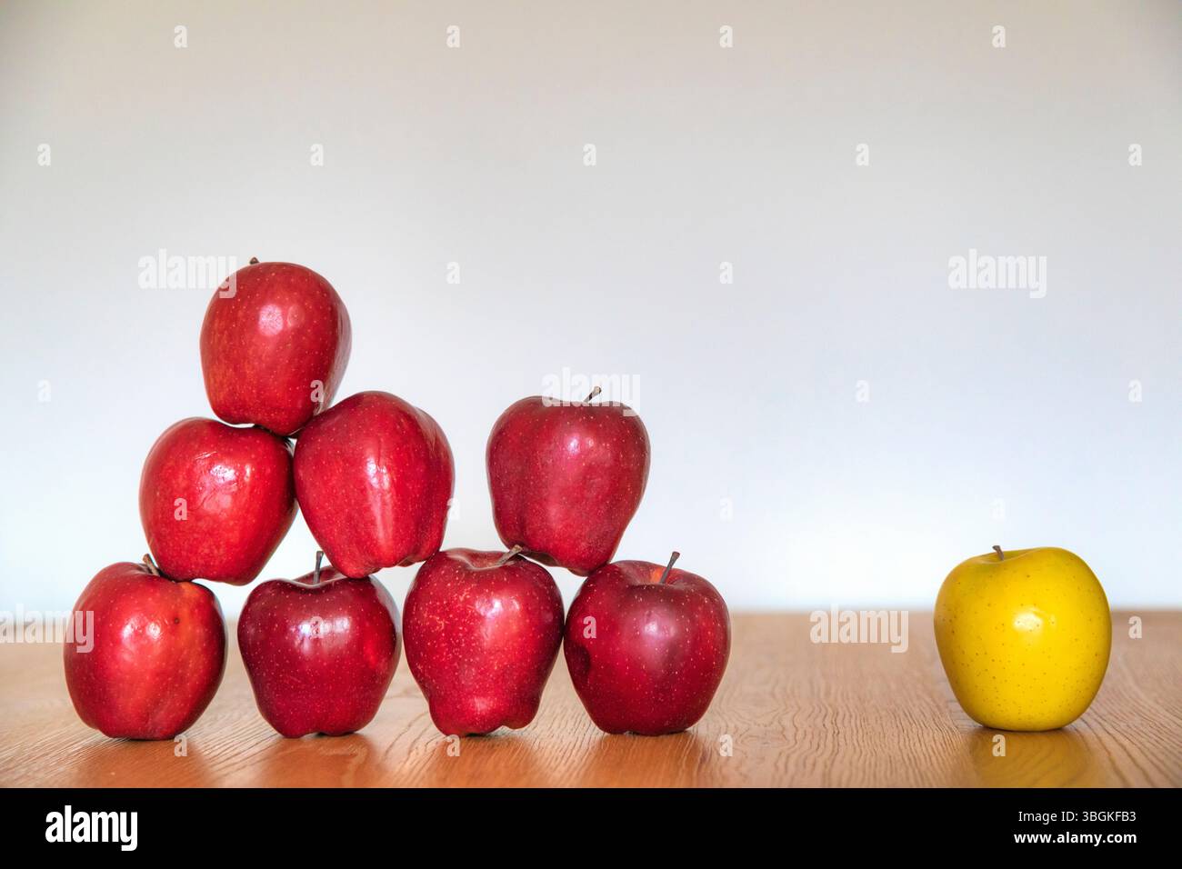 A pyramid of red apples and a solitary yellow apple, symbolizing the ...