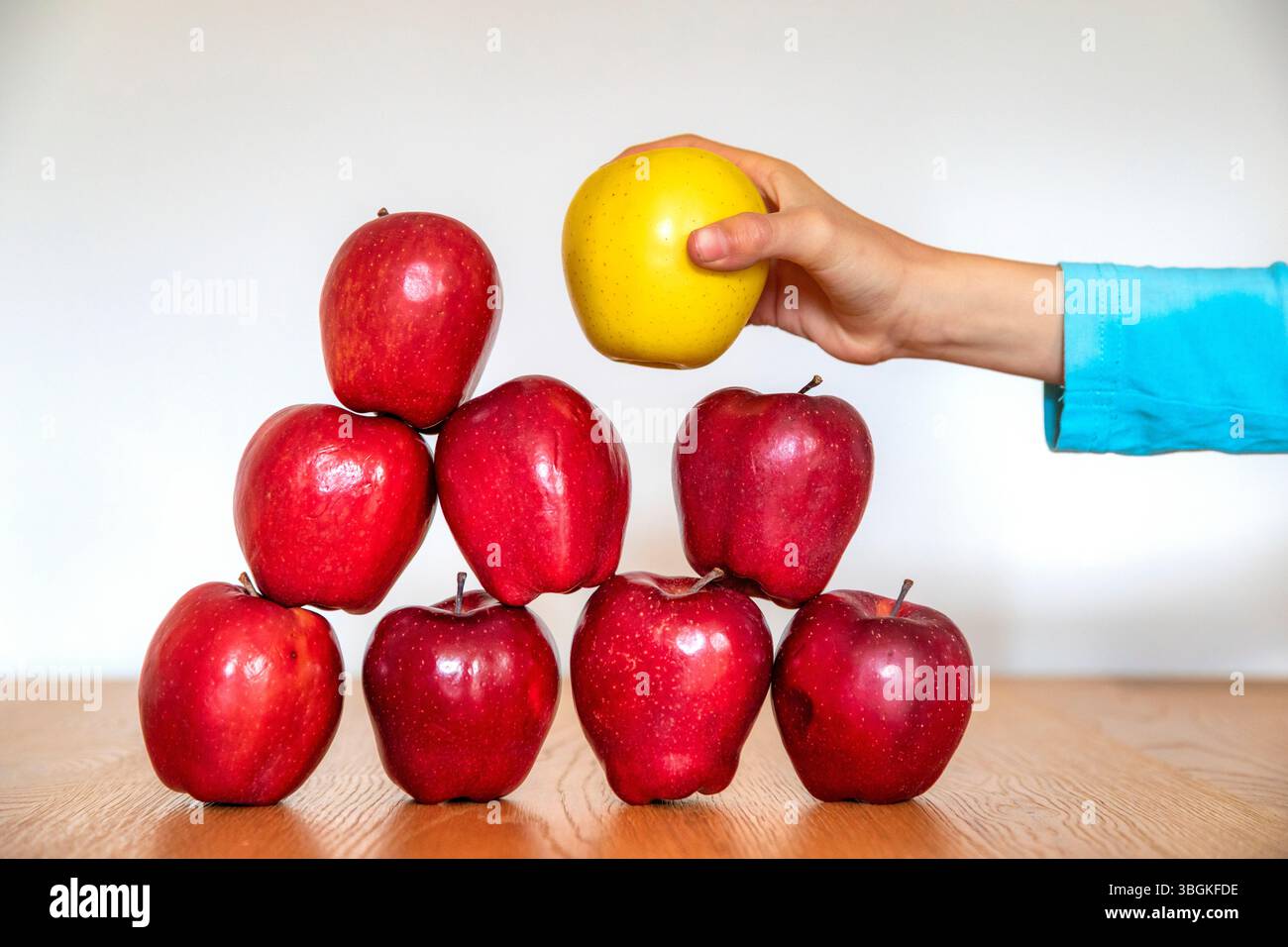 A pyramid of red apples and a solitary yellow apple, symbolizing the ...