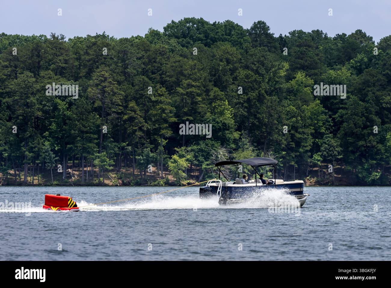 Pontoon boat pulling inflatable tube float raft on lake. Family on a ...