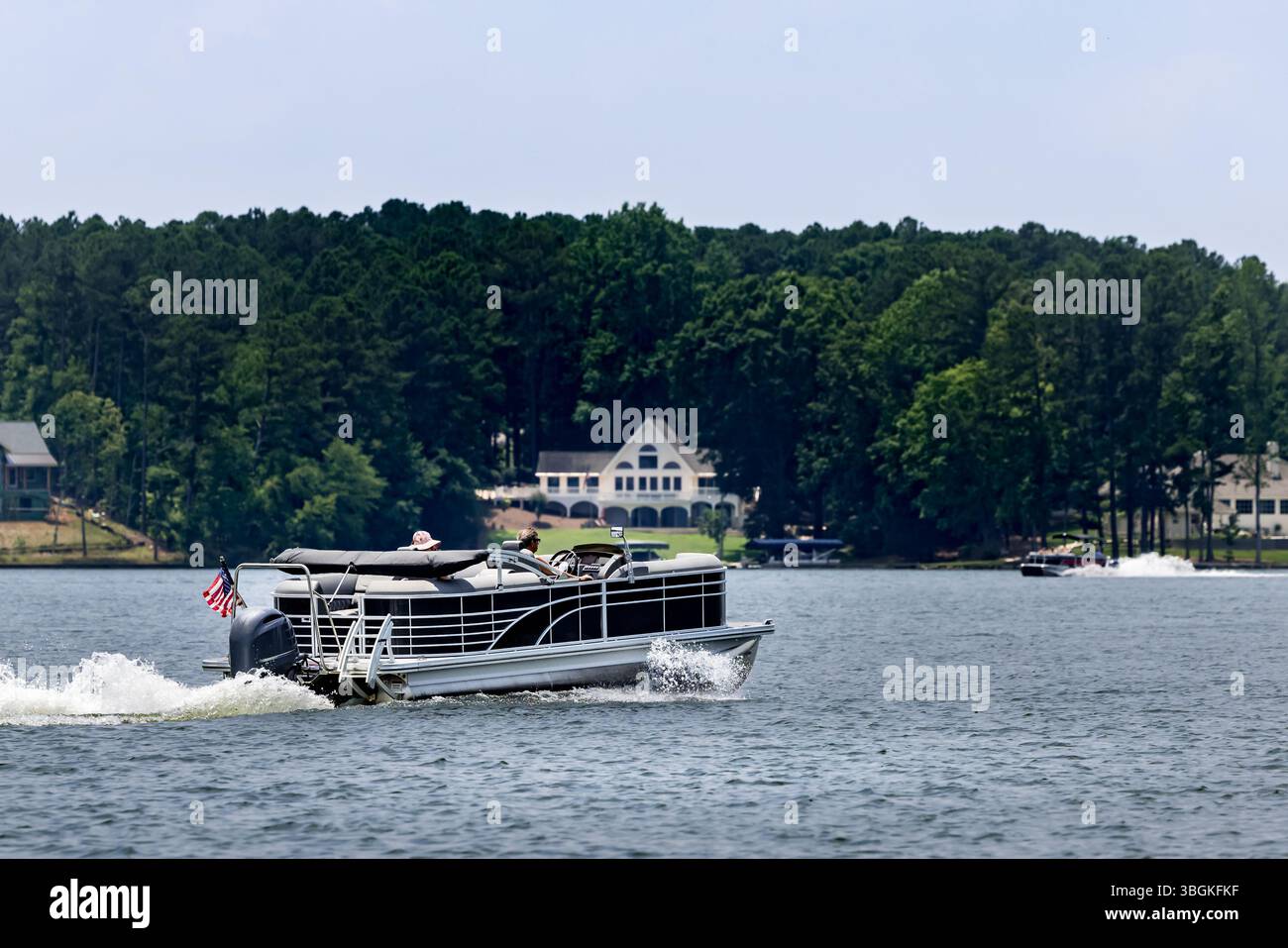 Pontoon boat pulling inflatable tube float raft on lake. Family on a ...