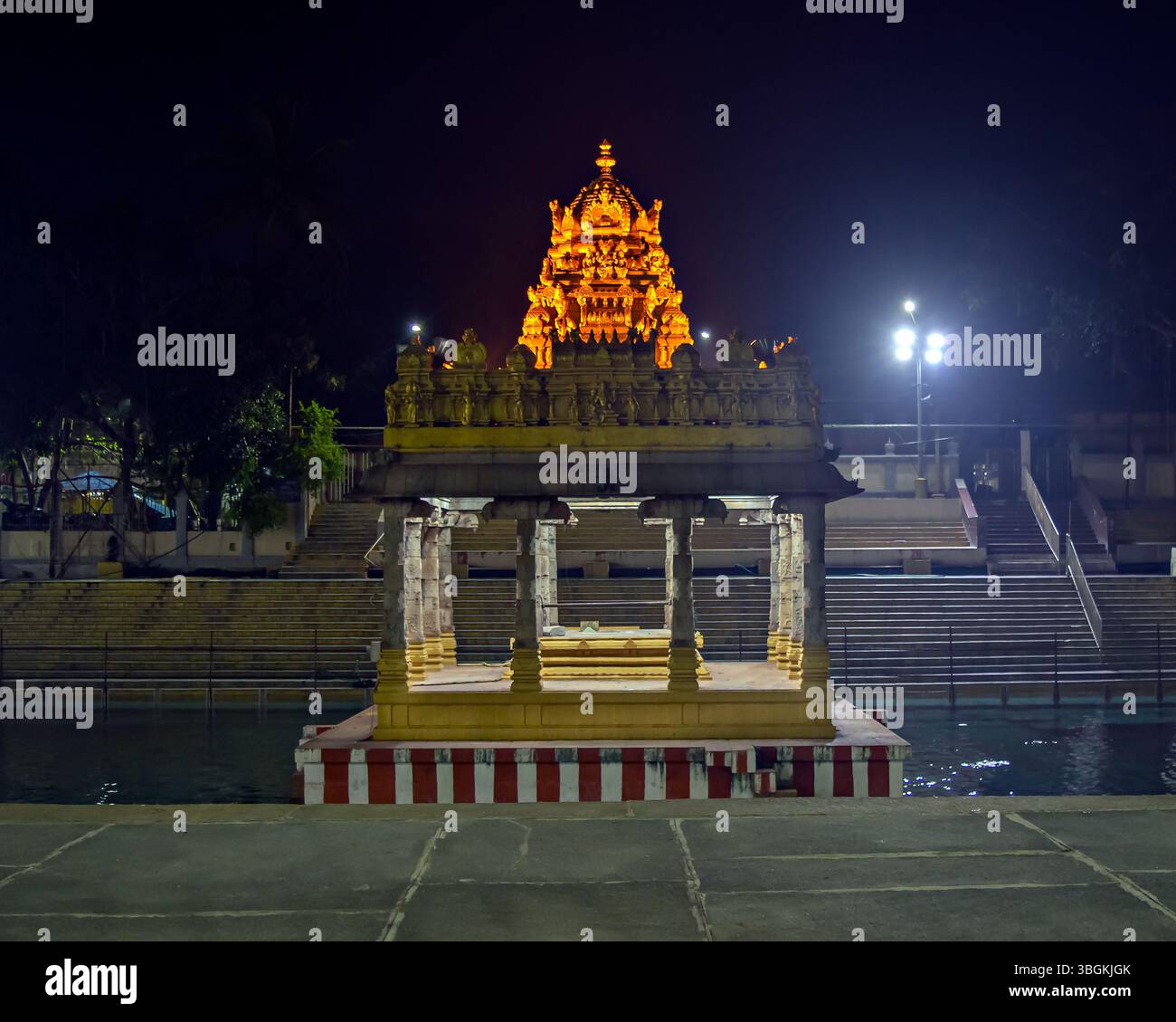 Night image of empty temple with golden dome in holy water pond at ...