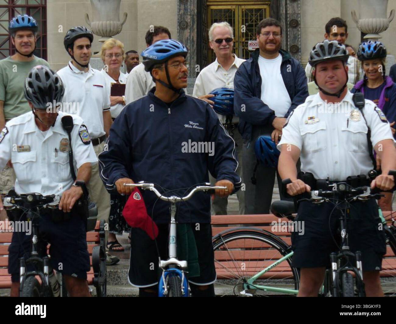 A photograph shows Mayor Coleman riding a bicycle, flanked by Columbus ...