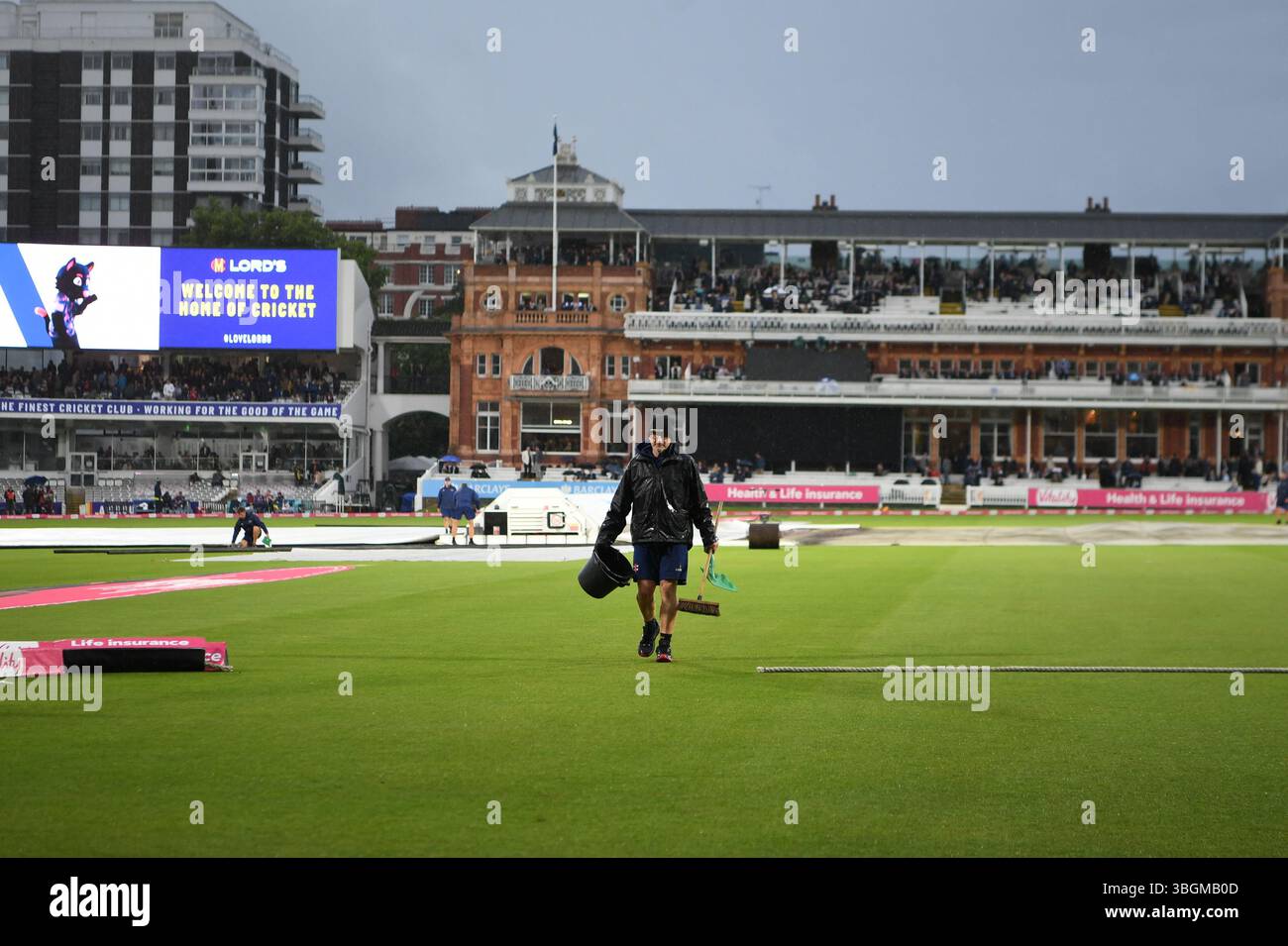 London, England. 5th June 2025. Groundstaff walk from the pitch as rain ...