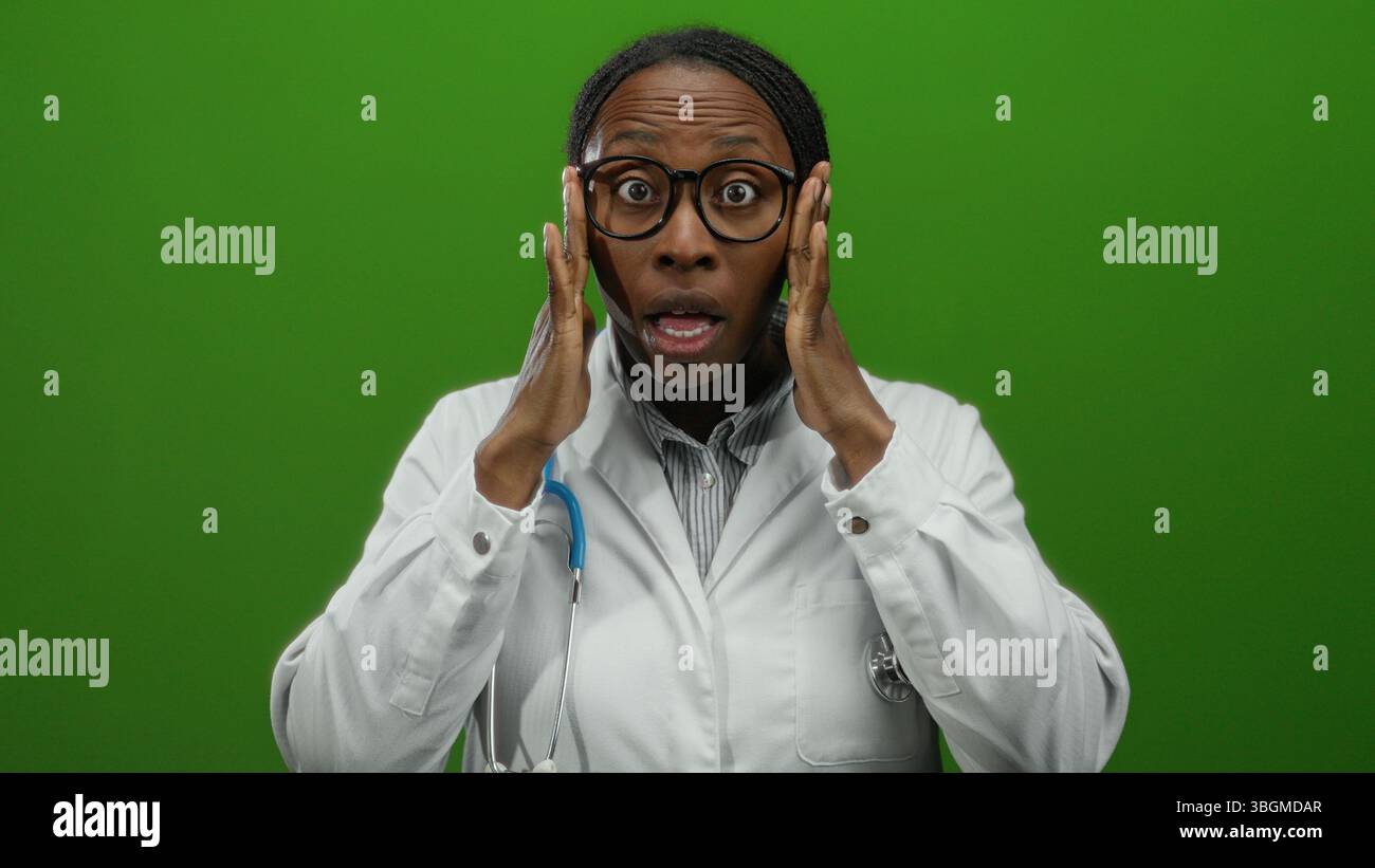 Doctor wearing glasses and stethoscope stands against green wall ...