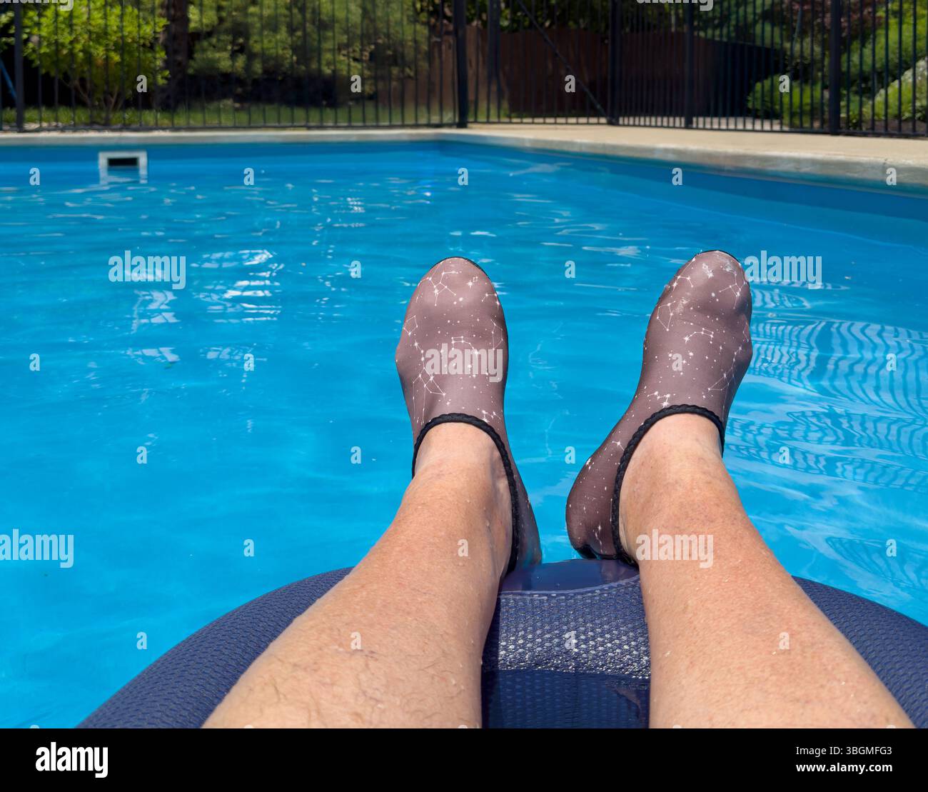 Legs and feet of caucasian man floating on blue raft in residential ...