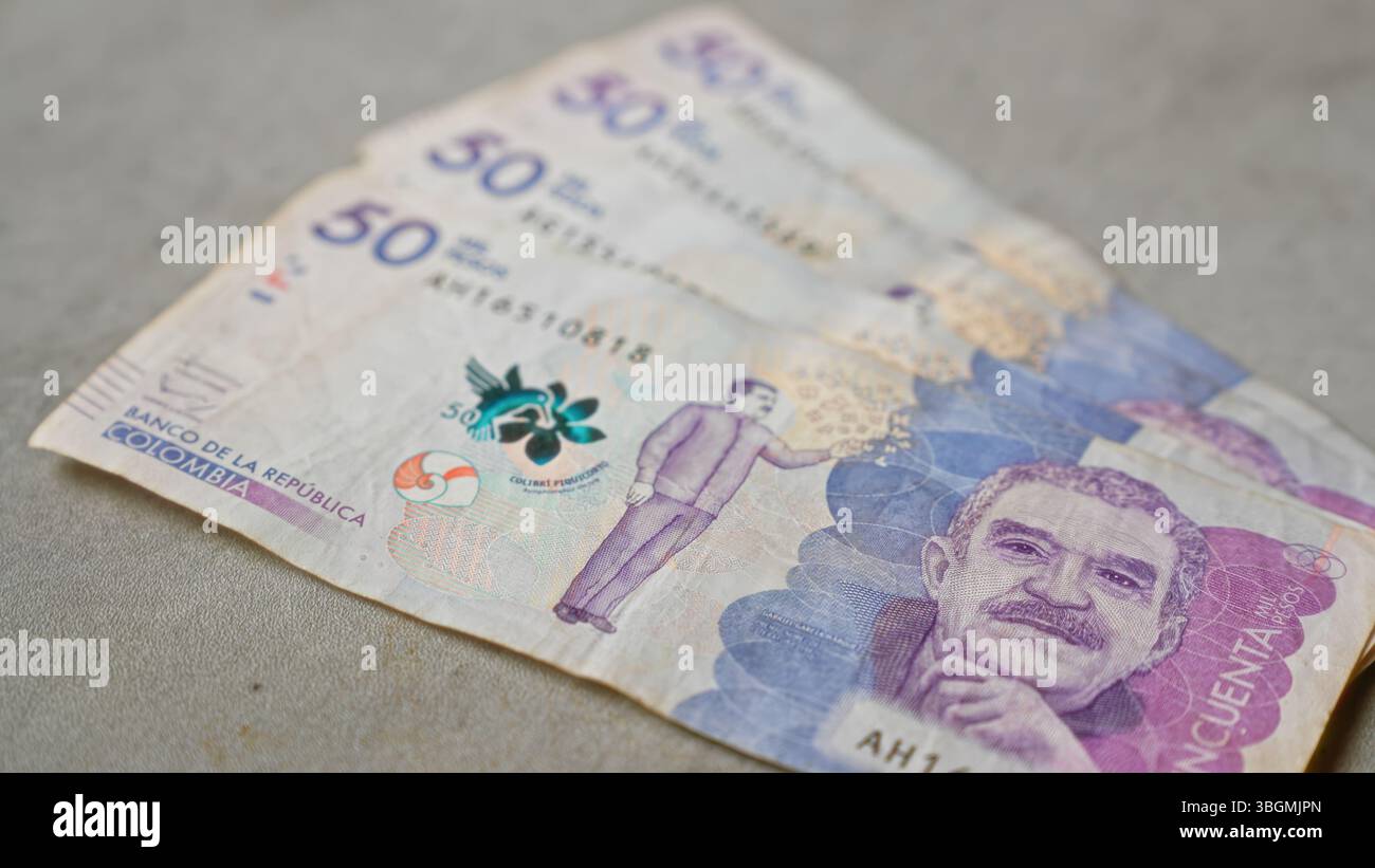 Colombian pesos illustrated with national figures lie on a concrete ...