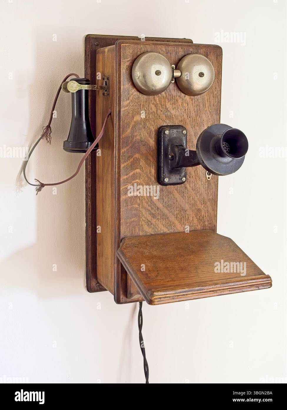 Early 20th century wood wall telephone hanging on white wall Stock ...