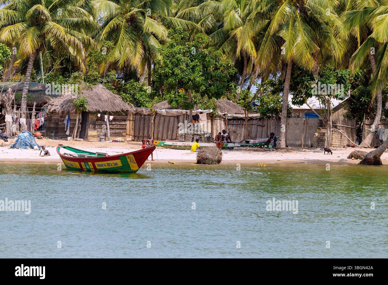 Ada Foah fishing village with thatched huts and colorfully painted boat ...