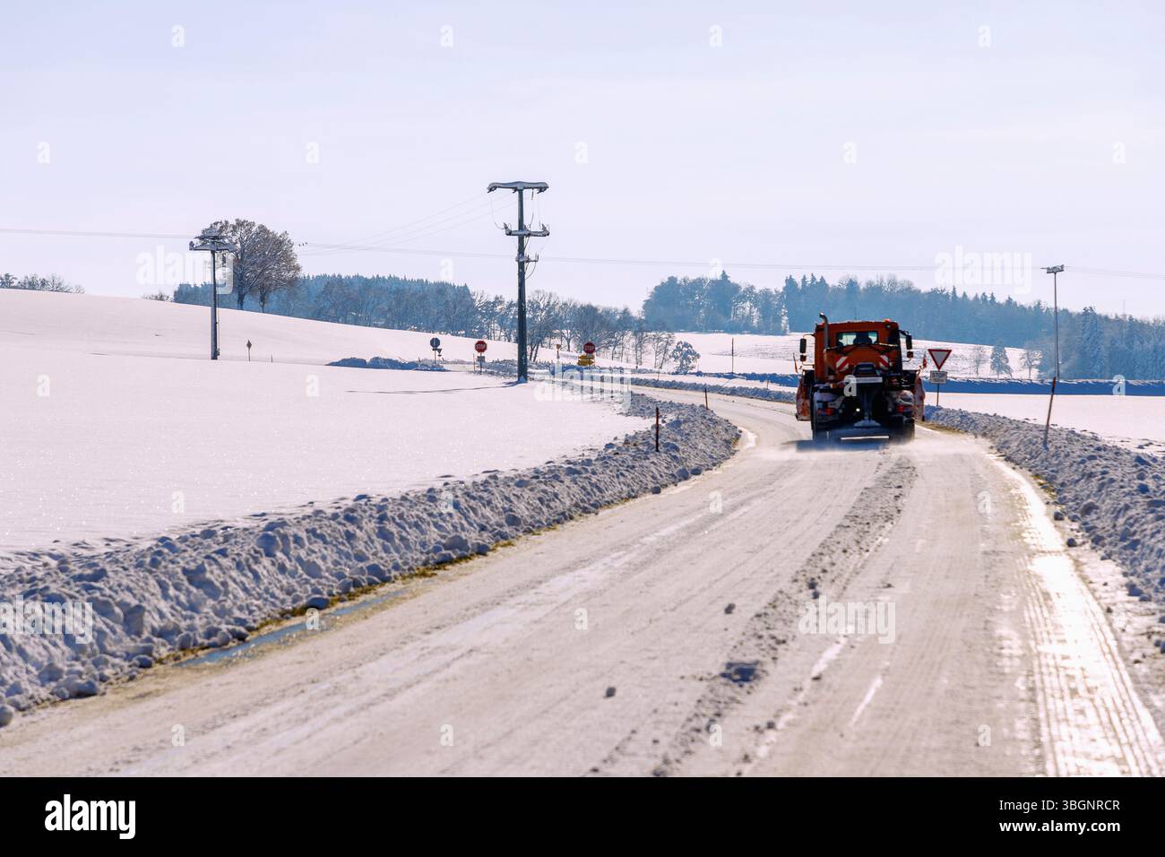Snowy landscape with road, gritting vehicle on winter service and snow ...
