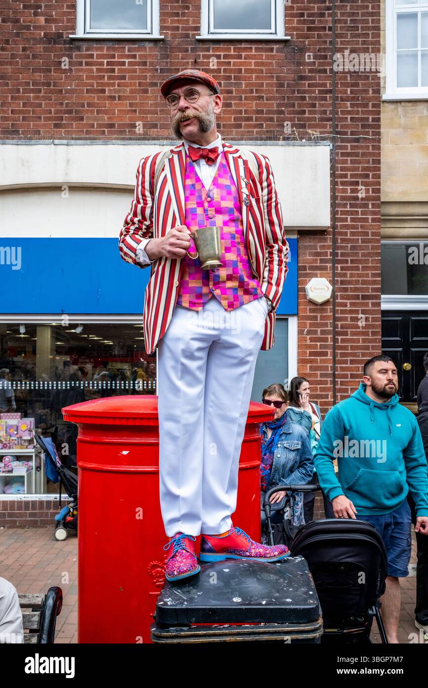 A Colourfully Dressed Man Stands On A Litter Bin For A Better View Of A ...