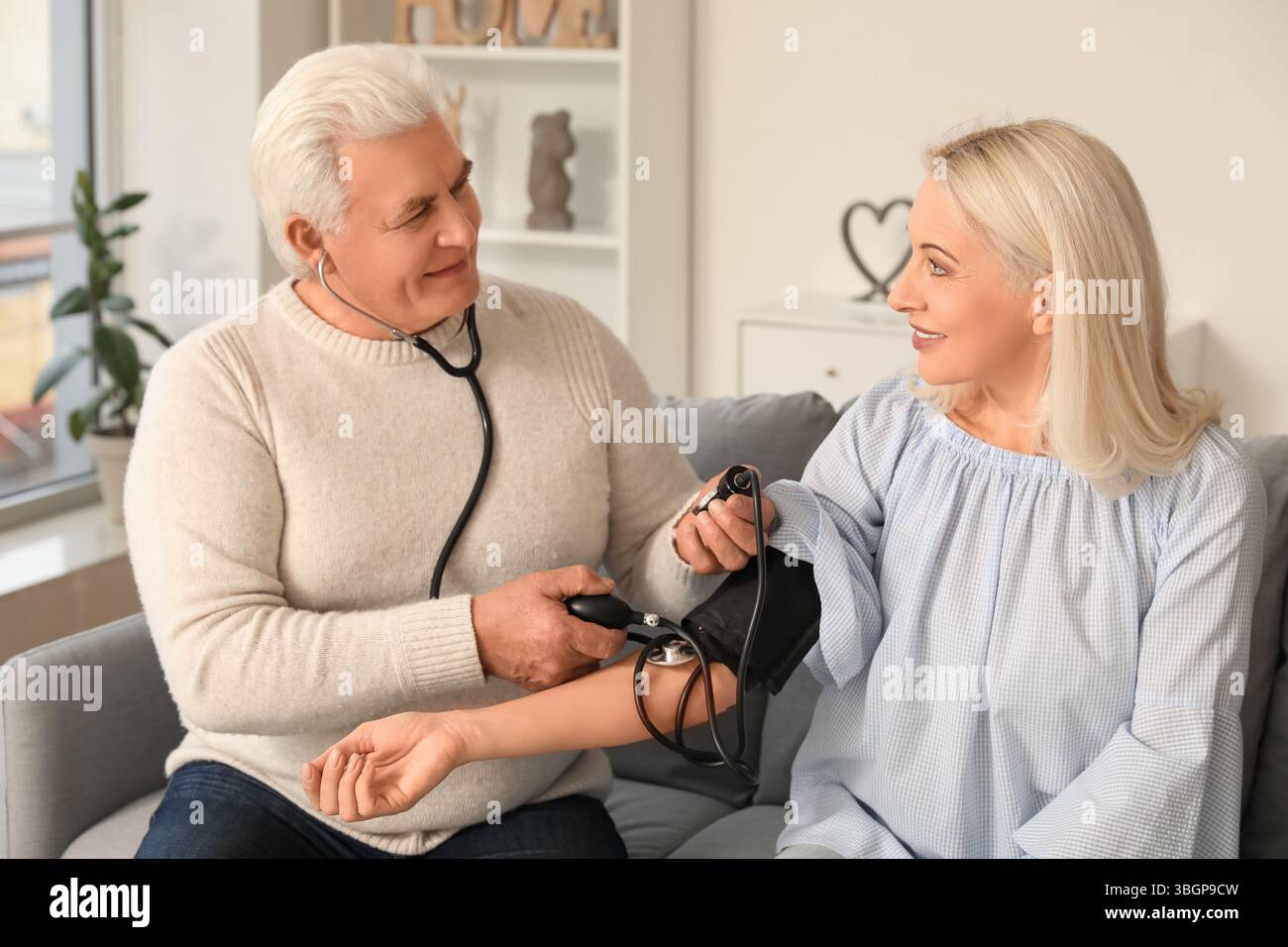 Mature man measuring blood pressure of his wife at home Stock Photo - Alamy