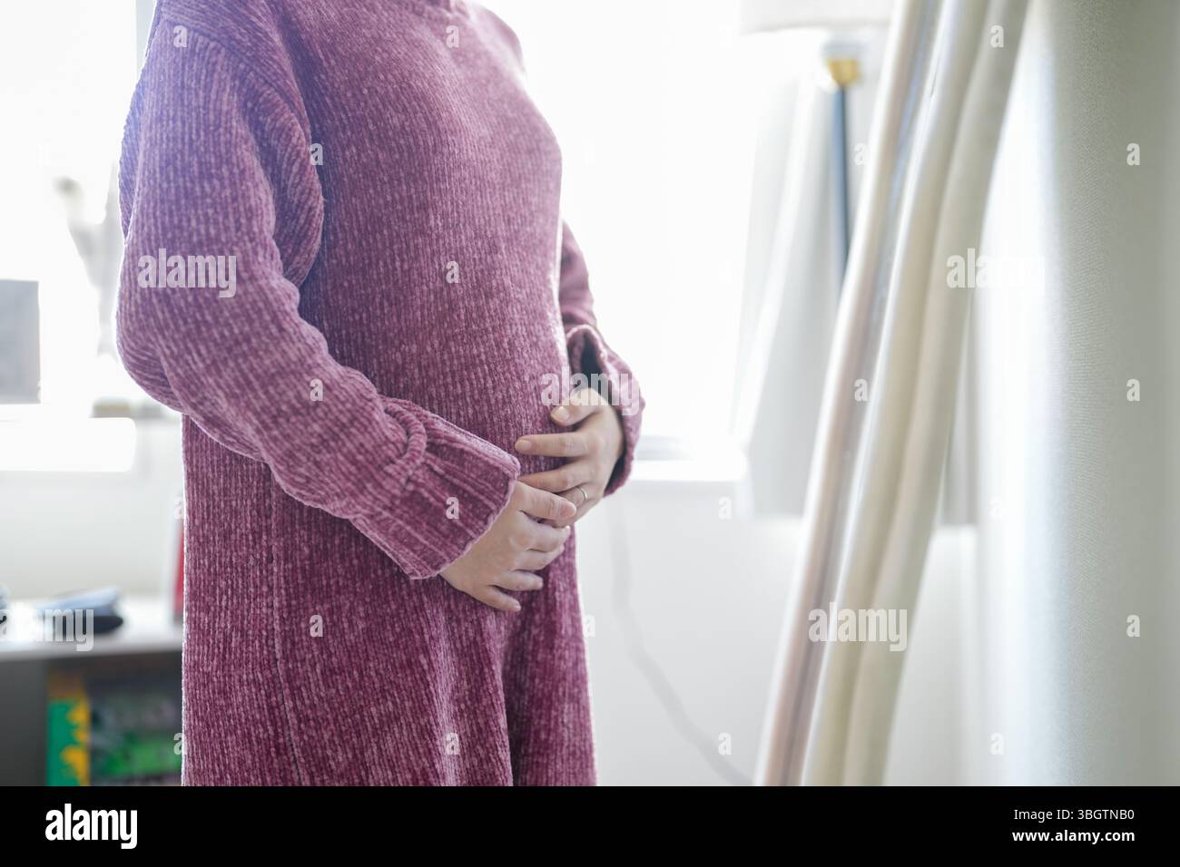 In a minimalist indoor setting, a pregnant Japanese woman in her early ...
