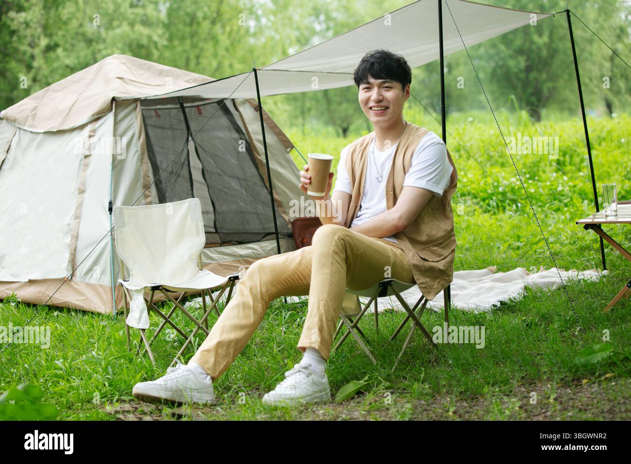 young man resting on an outdoor chair with a coffee cup in hand Stock ...