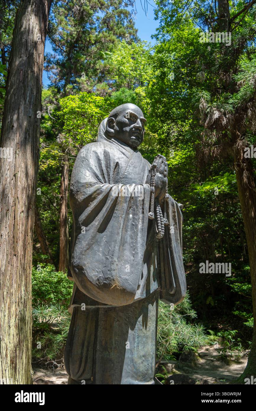 Tall bronze statues of monks stand solemnly in the forested grounds of ...