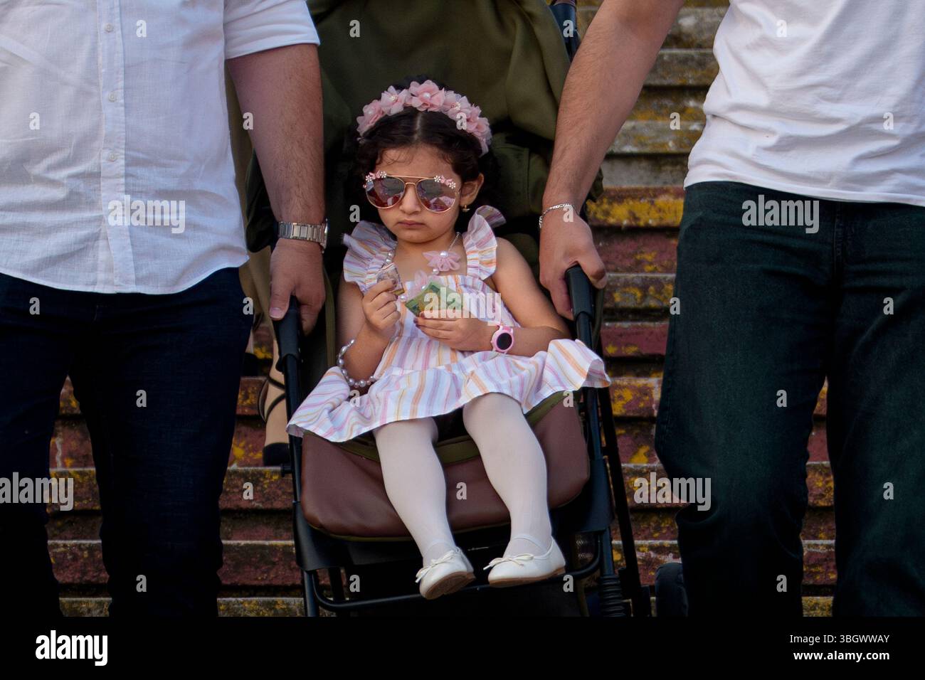 A child is carried in a stroller as people of the Muslim community in ...