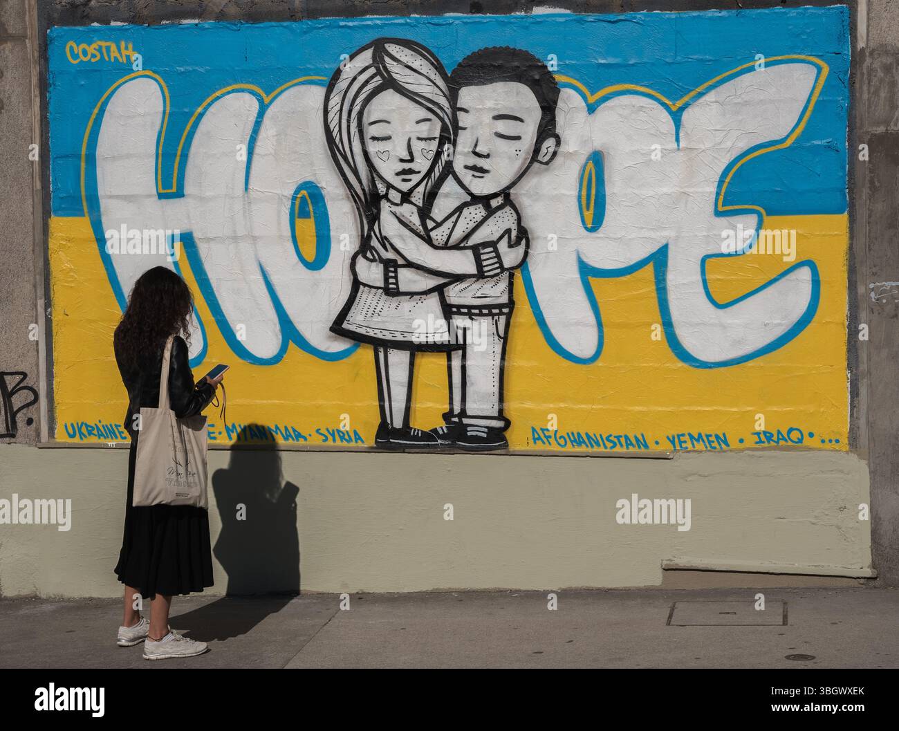 Young woman looking at hope street art dedicated to conflict and war ...