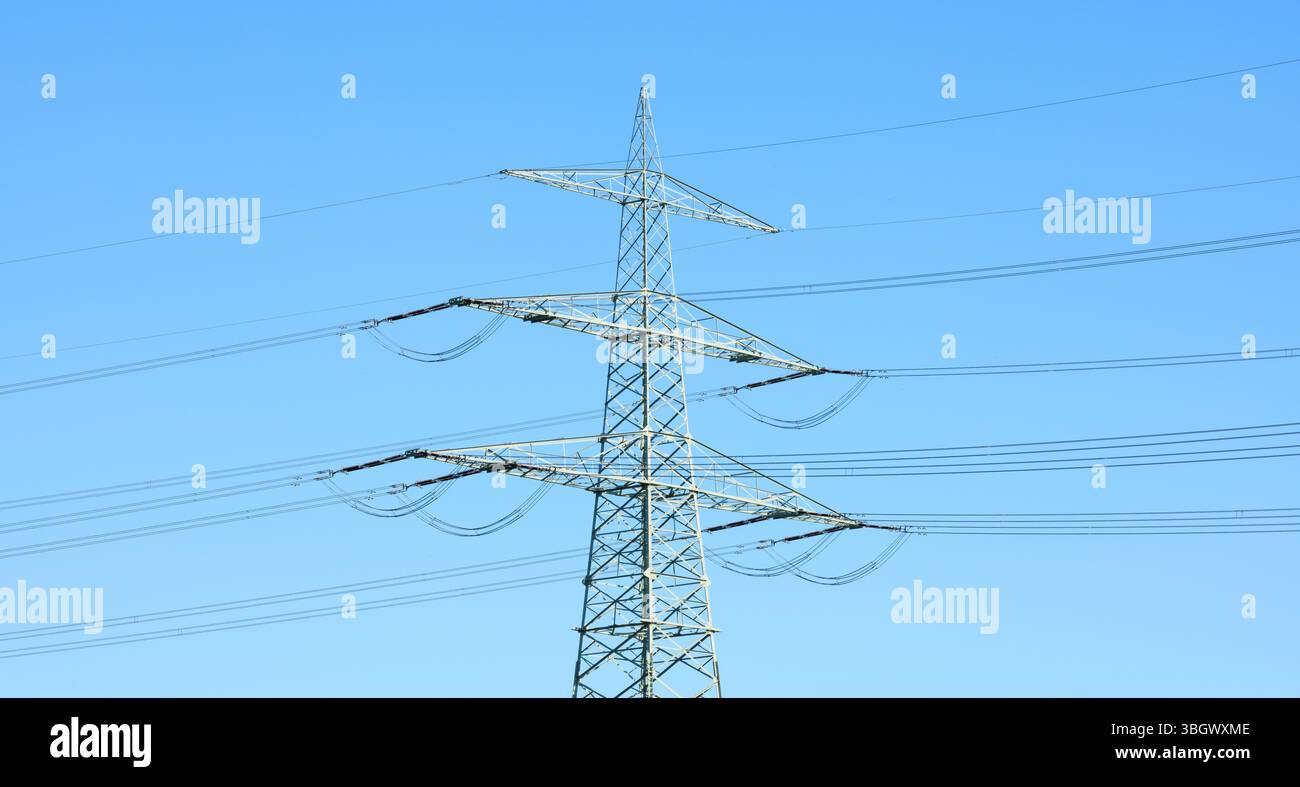 A massive high-voltage power mast in front of a clear sky symbolises ...